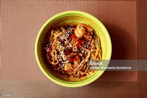 우동은 시끄러운 갈색 테이블 매트 배경에 녹색 접시 그릇에 야채 새우 참깨를 곁들인 국수를 볶습니다 평면도 클로즈업 0명에 대한 스톡 사진 및 기타 이미지 Istock