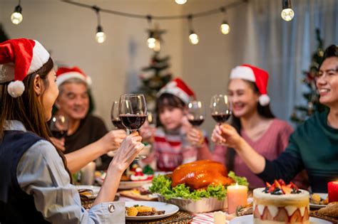 집에서 함께 크리스마스 파티를 축하하는 아시아 사랑스러운 가족 저녁 식사를하는 매력적인 부모와 친척 휴일 추수 감사절 식탁에서 크리스마스 이브를 축하하기 위해 와인 한 잔을