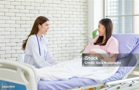 아시아의 젊은 여성 의사가 클리닉이나 병원에서 침대에 누워 있는 여성 환자의 손을 잡고 미소 짓는 돌보는 의사 의학 건강 관리