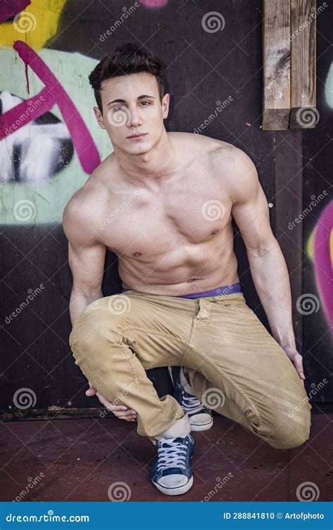 Photo Of A Muscular Man Striking A Pose In Front Of Vibrant Graffiti
