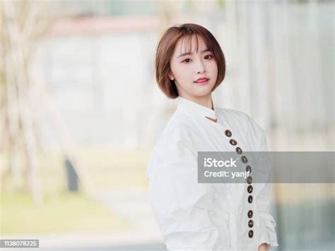 화창한 날에 카메라에 웃 고 흰색 셔츠에 아름 다운 젊은 갈색 머리 여자 매력적인 중국 쾌활 한 세련 된 여자의 야외 패션 초상화 감정 사람 아름다움과 라이프 스타일 개념