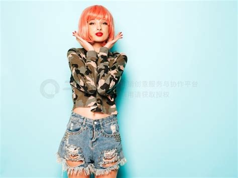 棒棒糖高清图片 年轻美丽的嬉皮士坏女孩的肖像，穿着时髦的牛仔裤短裤，鼻子上戴着耳环。性感无忧无虑的微笑女人戴着粉色假发在工作室里摆姿势。正模特玩得很开心 人像图片免费下载格式编号
