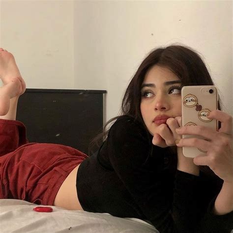 A Woman Laying On Her Bed Taking A Selfie With Her Cell Phone In Hand