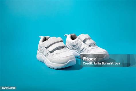 하드 햇빛과 파란색 종이 배경에 쉽게 신발을 신을 수있는 벨크로 패스너와 두 개의 흰색 아이 스포츠 신발의 전면 보기 0명에 대한 스톡 사진 및 기타 이미지 Istock