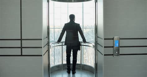 정장을 입은 젊은 우아한 사업가가 사무실 센터에서 휴식을 즐기면서 문이 열린 엘리베이터에 서 있다 사진 Unsplash의 서 이미지