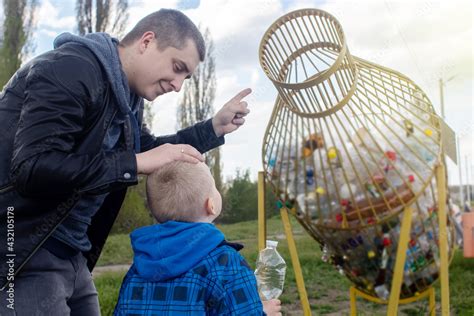 Dad And Son Throw The Plastic Bottle Into The Plastic Collection Container Recycling And