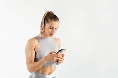 스튜디오에서 스포츠 여성의 초상화 빈 배경에있는 백인 소녀 운동과 근육 구축을위한 피트니스 개념 프로 운동 선수 소녀 파워 사진 사람은 훈련 휴대 전화를 위해 가젯을