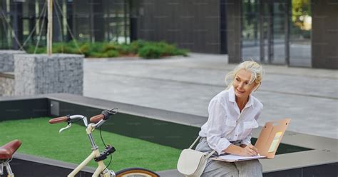 비즈니스 센터 앞에 앉아 있는 현대적인 자전거를 탄 흰 옷을 입은 잘 생긴 여성의 전체 길이 초상화 사진 Unsplash의 수송 이미지