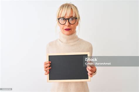 고립된 흰색 배경 위에 칠판을 들고 안경을 쓰고 있는 중년 여성이 스마트한 얼굴에 자신감 있는 표정을 지니고 있습니다 감정에 대한 스톡 사진 및 기타 이미지 Istock