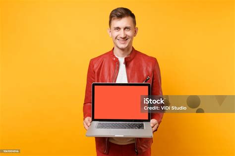 빨간색 가죽 재킷 T셔츠에서에서 젊은 남자 잡고 노트북 Pc 컴퓨터 빈 빈 화면이 밝은 노란색 배경에 절연 세로 보 그 재미 사람들이 진심으 감정 라이프 스타일 개념 광고