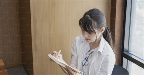 거실의 의자에 앉아 일기를 쓰는 캐주얼한 젊은 여성의 초상화 사진 Unsplash의 홈 오피스 이미지