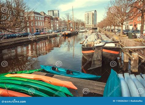 Canal Of Historical Dutch City With Moored Boats And Canoe Riverboats