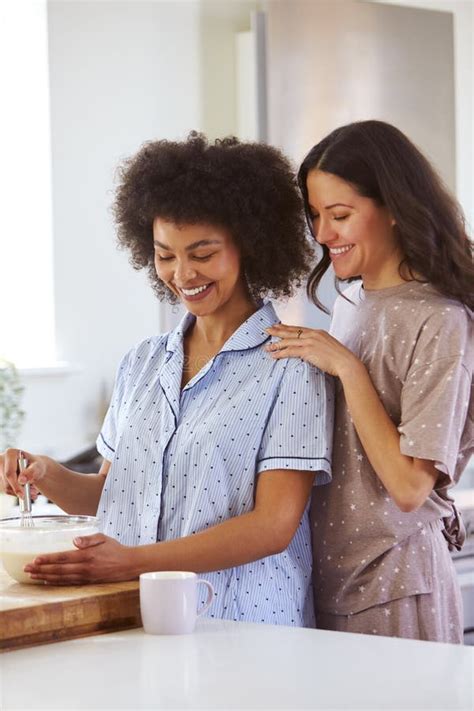 Loving Same Sex Female Couple Wearing Pyjamas Making Morning Pancakes