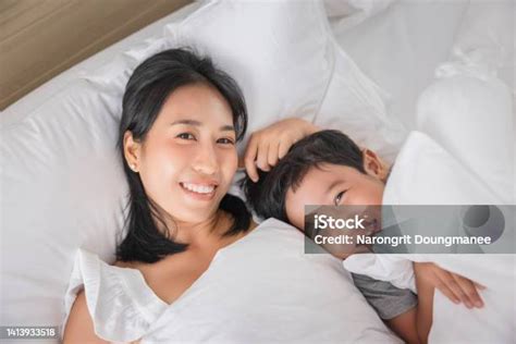 젊은 아시아 여성과 아들은 침대에서 자고 침실에서 휴식을 취합니다 그들은 옆으로 누워서 눈을 감고 긴장을 풀고 있습니다 카메라를보고 아시아에 대한 스톡 사진 및 기타 이미지
