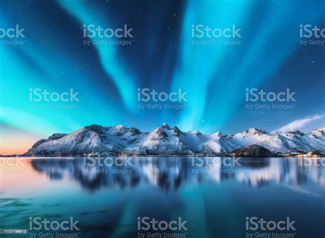 오로라와 눈 Lofoten 섬 노르웨이 산 포함 오로라 보 리 얼 리스입니다 극 지 빛과 눈 덮인 바위와 별이 빛나는 하늘 물에