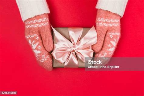 따뜻한 니트 장갑에 여자의 손은 빨간 배경에 공예 종이와 분홍색 리본으로 포장 선물 상자를 개최합니다 2020년에 대한 스톡 사진 및 기타 이미지 Istock