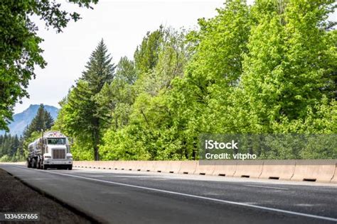 하루에 택시 흰색 큰 장비 산업 세미 트럭 은 측면에 숲과 직선 고속도로 도로에서 실행 두 탱크 세미 트레일러에 인화성 액체화물을 수송 0명에 대한 스톡 사진 및 기타