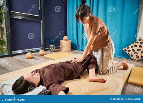 Masseuse Making Thai Yoga Massage Treatment Stretching Female Patient