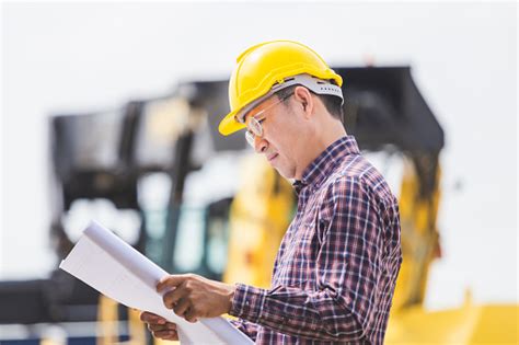 산업 화물의 컨테이너를 검사하고 검사하는 엔지니어 남자 안전모를 쓴 감독은 화물에서 컨테이너 상자를 적재하는 것을 제어합니다