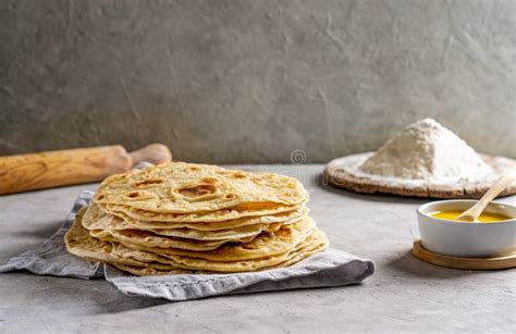 Homemade Indian Chapati Or Roti On Grey Concrete Background With Human Hand Pouring Butter Ghee