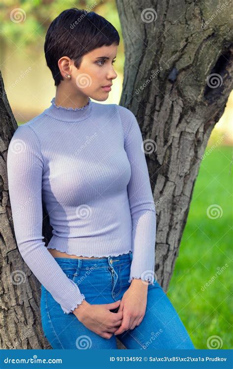 Красивая девушка при короткие волосы отдыхая около дерева весной Стоковое Фото изображение