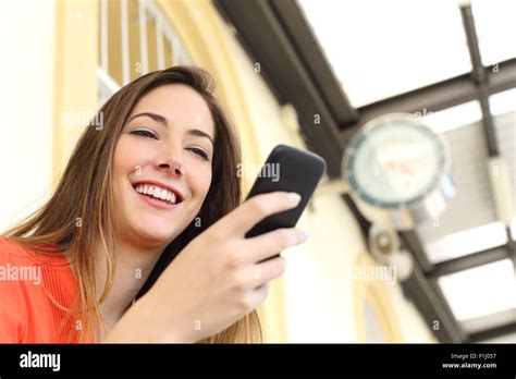 Woman Buying Ticket With A Mobile Phone In A Train Or Bus Station With A Clock In The Background