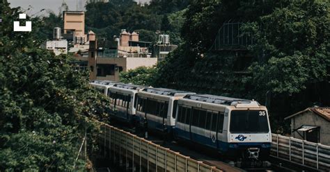낮에는 푸른 나무 근처의 철도 도로를 달리는 흰색과 검은색 기차 사진 Unsplash의 무료 건물 이미지