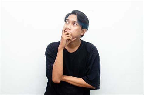 사려 깊은 아시아 남자는 붉은 배경 위에 고립된 생각 제스처로 피부를 만지는 손으로 생각하고 궁금해합니다 20 24세에 대한