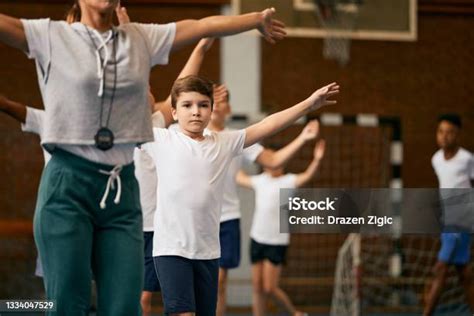 초등학생과 그의 친구들은 학교 체육관에서 코치와 함께 체육 수업을 하는 동안 워밍업 아이에 대한 스톡 사진 및 기타 이미지 아이 체육 학교 체육관 Istock