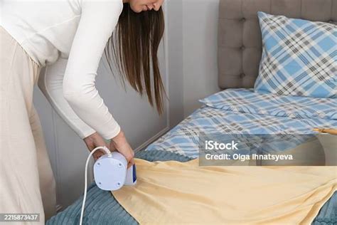 아늑한 침실의 침대에서 노란색 드레스를 입고 주름 없는 옷을 만들고 일상을 위해 단정하고 단정한 외모를 유지하는 젊은 여성 25 29세에 대한 스톡 사진 및 기타 이미지