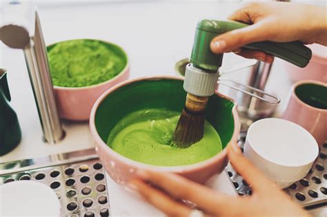 현대 전기 거품기로 채찍질하는 말차 분말의 공정 바리스타는 아시아 카페에서 현대적인 티웨어 도구를 사용하여 천연 거품 이마 차를 만듭니다 채식 카페에서 천연 녹차 준비