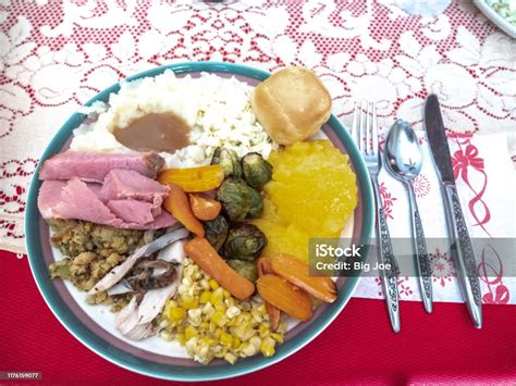 당근 옥수수 칠면조 스터핑 햄 젤로 으깬 감자 그레이비 등 다양한 음식을 붉은 색 장식 테이블 천으로 장식하여 휴일 저녁 식사를 즐기는 모습 가득 찬에 대한 스톡 사진 및