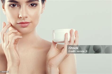 여자 얼굴 피부 관리 매력적인 젊은 여성의 초상화 크림을 적용 하 고 병을 들고 자연 메이크업과 신선한 피부와 미소 소녀의