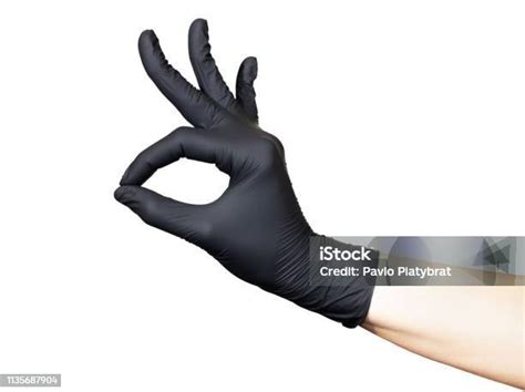 검은 장갑에 여자 손은 흰색 바탕에 확인 표시를 보여줍니다 엄지 손가락과 검지 손가락이 고리에 닫혀 있고 다른 세 손가락은 위로 올려 있습니다 후면 보기 몸짓에 대한 스톡