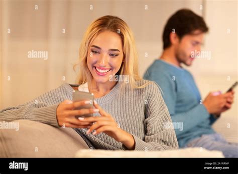 Unfaithful Girlfriend Chatting On Phone Sitting Next To Boyfriend