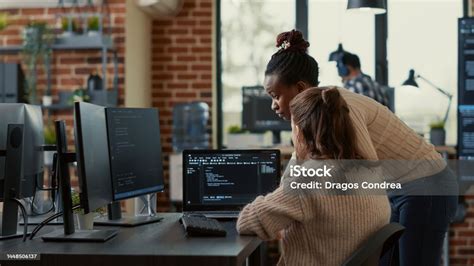 Two System Engineers Analyzing Source Code On Laptop Looking For Errors