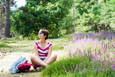 여름 숲에서 하이킹을 마친 후 휴식을 취하는 한 여성 꽃과 함께 초원에서 태양을 즐길 수 있습니다 자연과의 단합 디지털 해독
