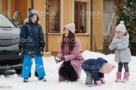 젊은 어머니는 겨울에 그녀의 집의 마당에서 전기 자동차에 대해 아이들과 놀고 있습니다 가족에 대한 스톡 사진 및 기타 이미지 가족 겨울 차 Istock
