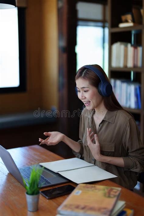 Portrait Of A Smiling Asian Teenage Girl Wearing Headphones And Using A