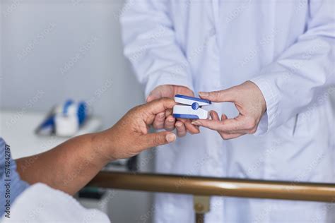 Side View Of Nurse Measuring Oxygen Saturation Of Senior Female Patient In Hospital Close Up