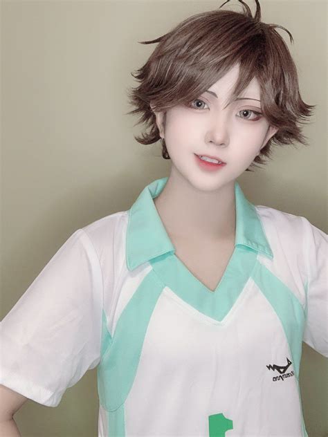 A Woman With Short Hair Wearing A White And Green Shirt