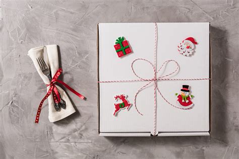 빨간 흰색 끈또는 크리스마스 장난감꼬기로 묶인 어린이 피자의 닫힌 상자 장식 회색 콘크리트 배경입니다 포크와 나이프테이블 세팅