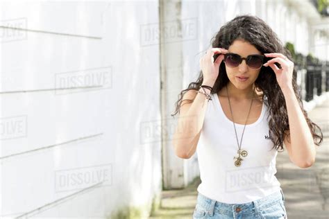 Young Woman With Long Wavy Hair Strolling On Street Putting On