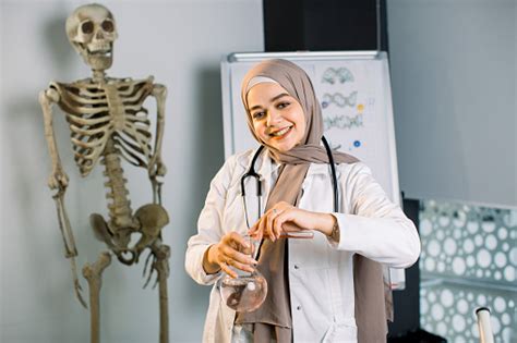 젊은 무슬림 여성 과학자 화학자는 두 가지 화학 물질을 혼합 손에 플라스크와 Trst 튜브를 들고 과학 실험을 준비 실험실에서 일하는 흰색 코트의 아랍 여성 과학자 Stem