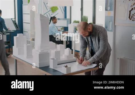 Man Architect Taking Notes On Blueprints Plan To Design Building Structure And Model Stock Video