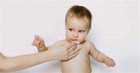 젊은 엄마는 흰색 배경에 물티슈로 아기 피부 몸과 얼굴을 조심스럽게 닦고 있습니다 컨셉 클리닝 와이프 순수하고 깨끗합니다