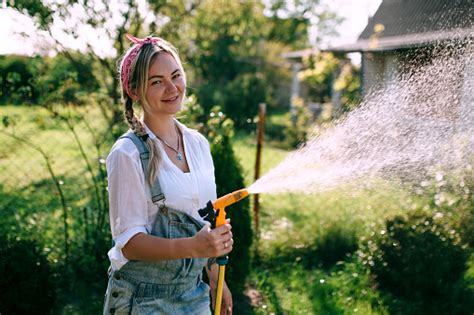 흰색 셔츠와 데님 바지를 입은 한 젊은 여성이 잔디밭에 물을 주었습니다 원예 컨셉과 조경 디자인 녹색에 대한 스톡 사진 및 기타 이미지 Istock