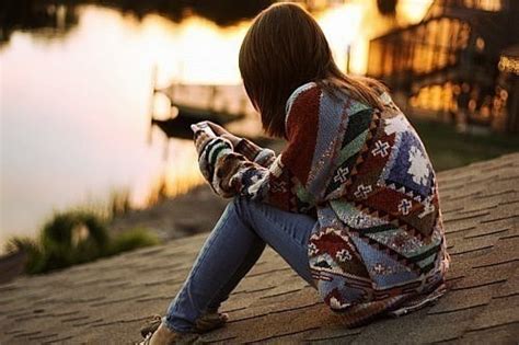 Фото Девушка с телефоном в руках сидит у воды