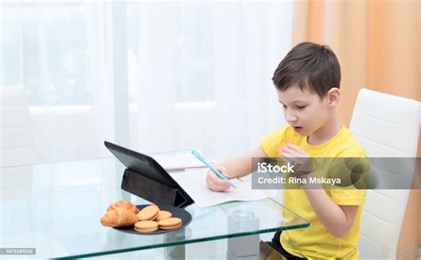 노란색 티셔츠를 입은 남학생이 집에서 공부하는 디지털 태블릿을 들고 테이블에 앉아 있다 원격 학습 온라인 교육 개념 6 7 살에 대한 스톡 사진 및 기타 이미지 Istock