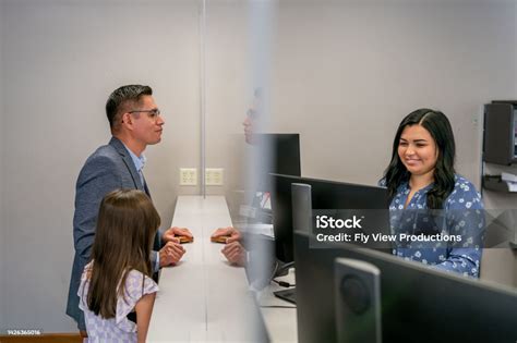 사무실 리셉션 데스크에서 체크인하는 라틴 아메리카 남성과 딸 은행 창구 직원에 대한 스톡 사진 및 기타 이미지 은행 창구 직원 은행업무 고객 Istock